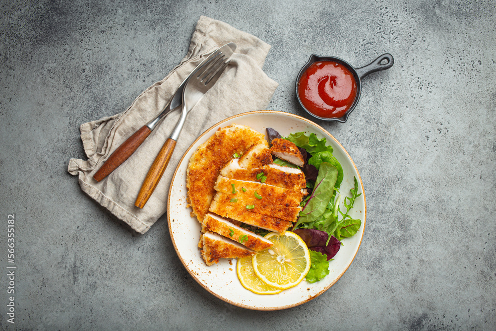 Crispy panko breaded fried chicken fillet with green salad and lemon ...