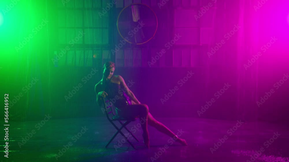 Slim woman performing erotic dance tricks sensually in colorful ...