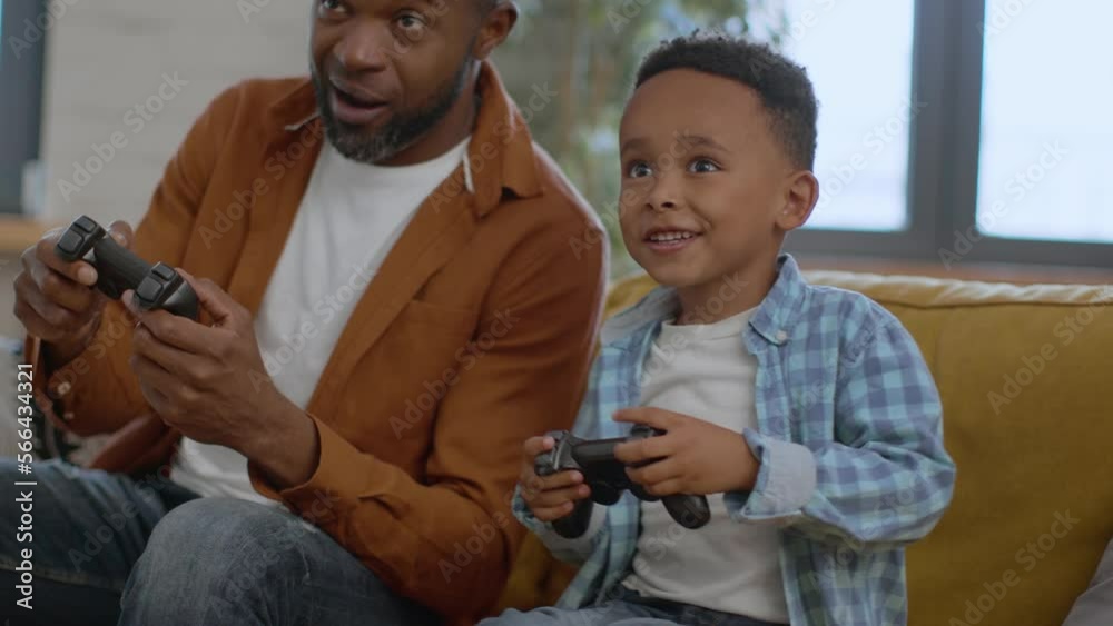 Cute little african american boy playing video games with joystick at ...