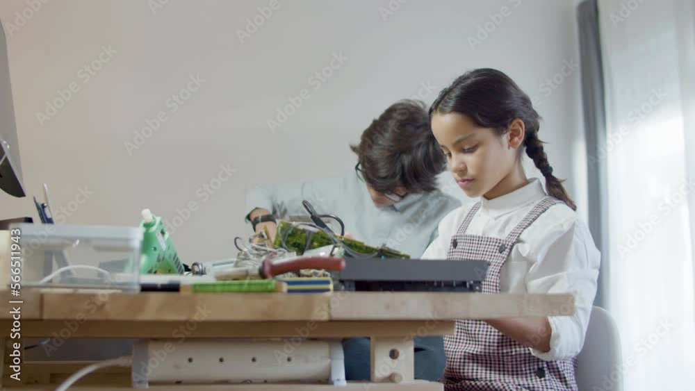 Two children doing educational project at home at daytime. Dark-haired ...