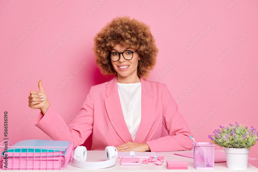 Portrait of creative female designer keeps thumb up in agreement of a ...
