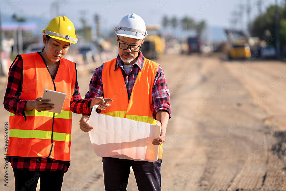 Female foreman looking at construction drawings with male engineer Wear ...