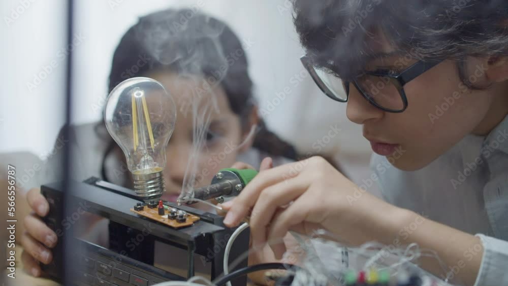 Two smart kids practicing their hobby in electrical engineering. Boy in ...