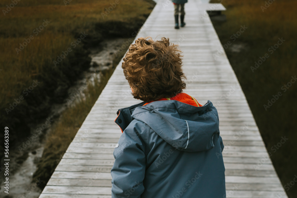 Rear view of child with curly hair on boardwalk Stock Photo | Adobe Stock