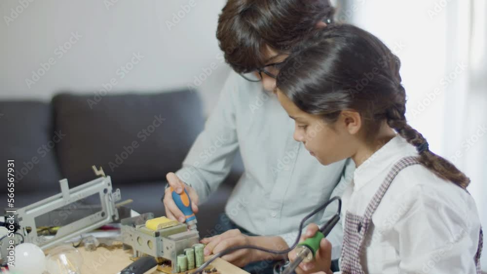 Two schoolchildren doing school project together. Boy in glasses using ...