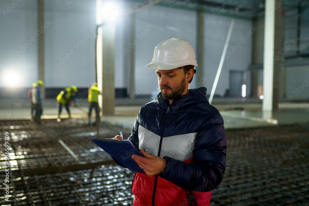 Professional builder in a hard hat with a notepad. Construction of an ...