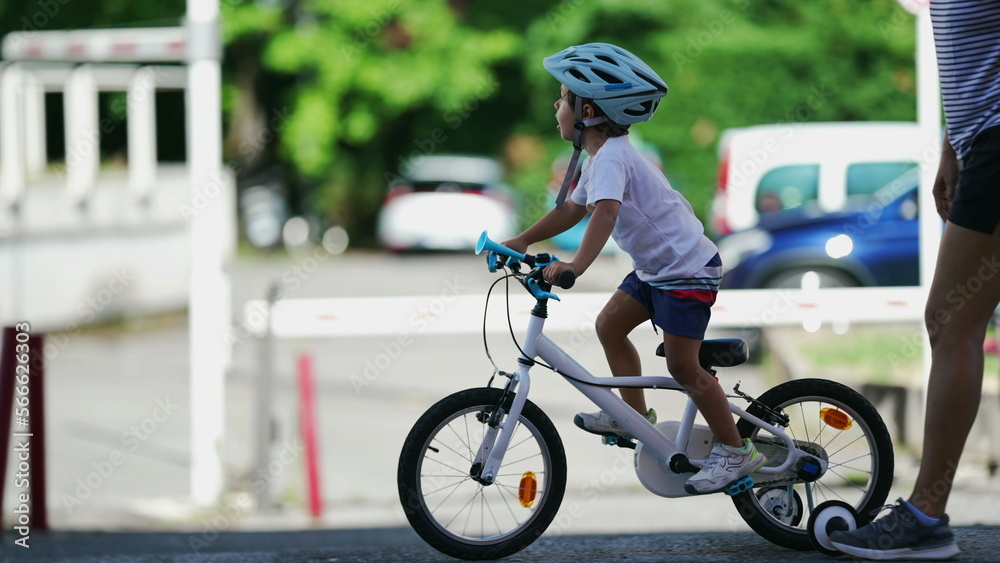 Child cyclist riding at sidewalk. Young boy wearing protective helmet ...