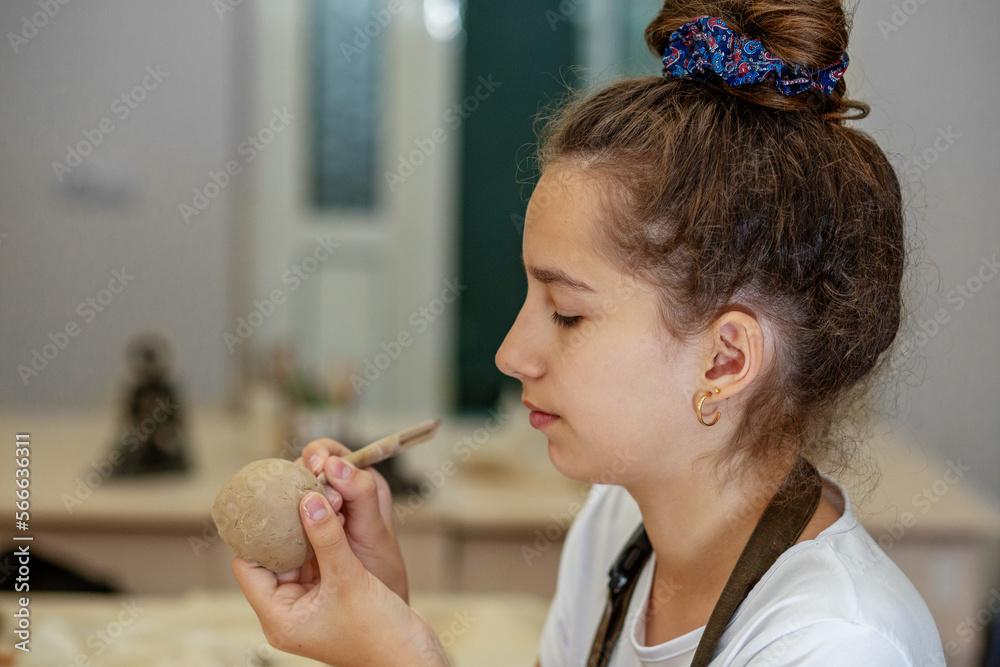 Beautiful teenage girl playing with modeling clay in pottery workshop ...