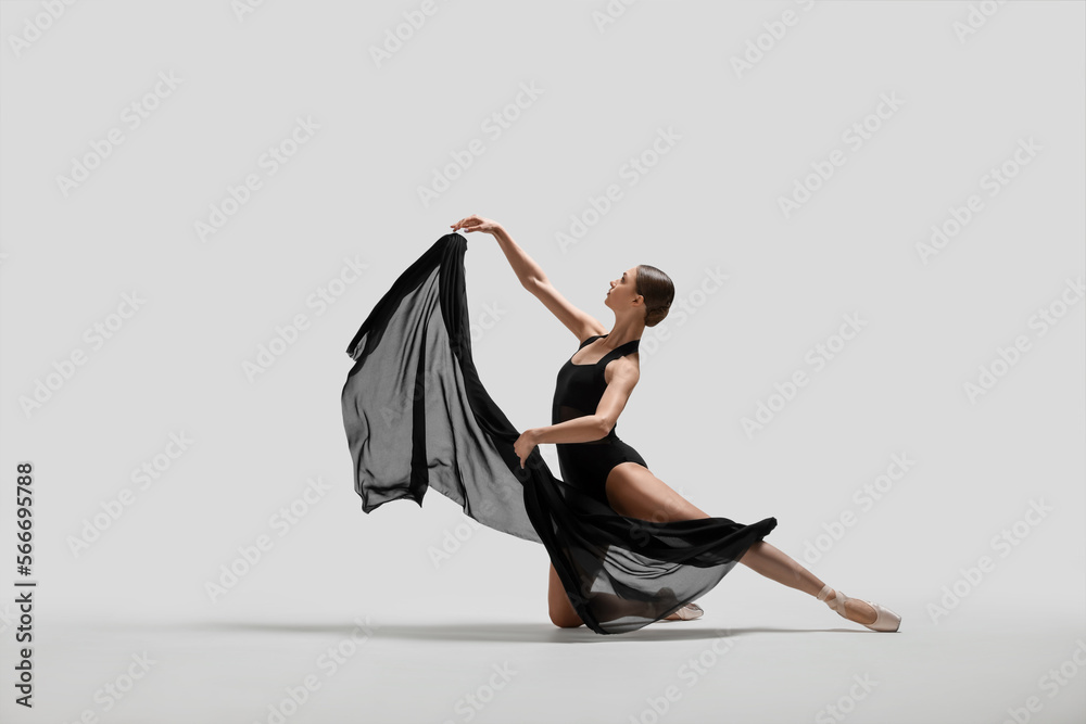 Graceful young ballerina practicing dance moves with black veil on ...