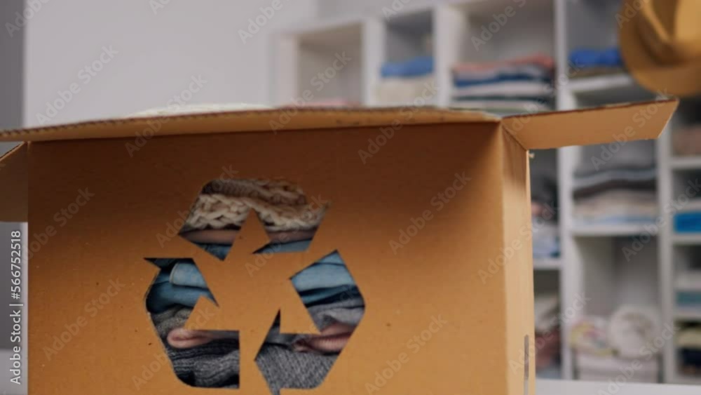 Hands put things of sustainable fabric in box with recycling sign ...
