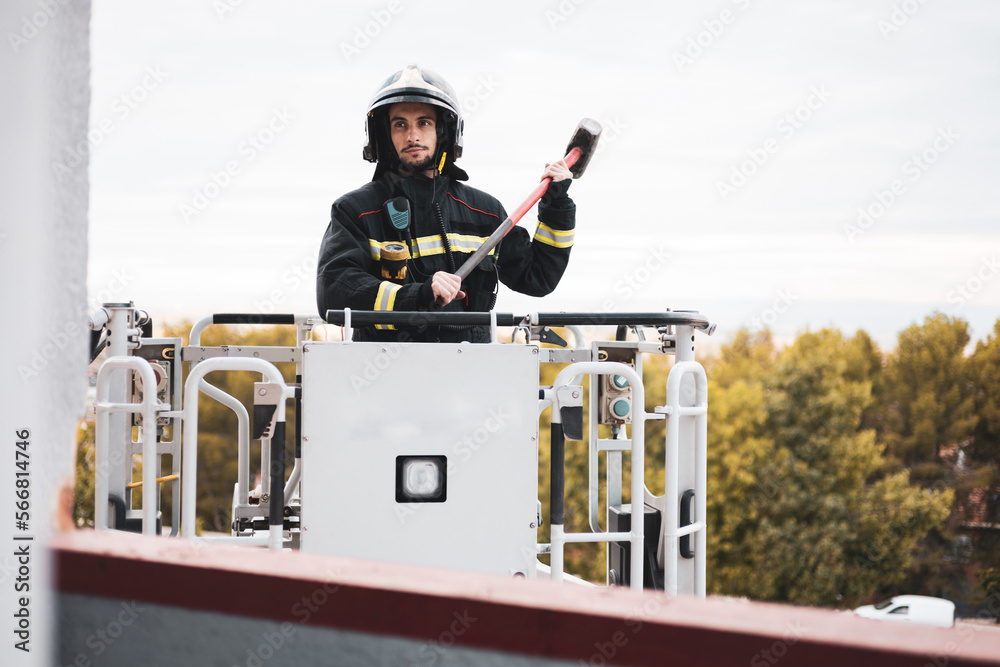 A Caucasian firefighter is prepared with a sledgehammer to break a ...