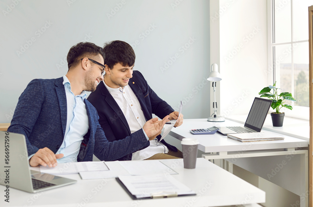 Team work. Two male office workers are reviewing documents together ...