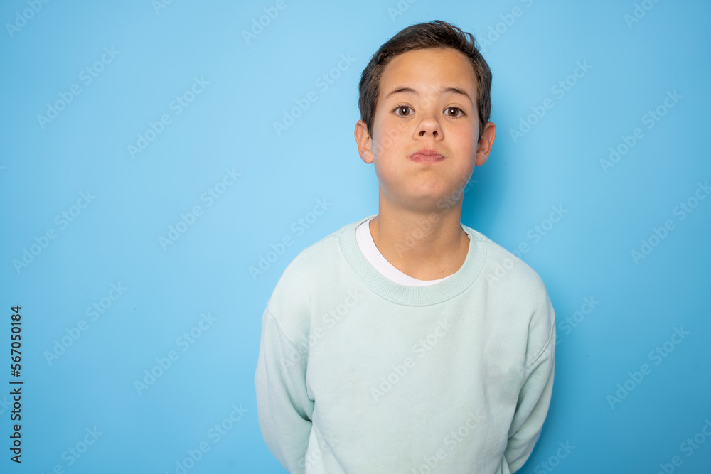 Beautiful kid boy wearing casual sweater standing over isolated blue ...