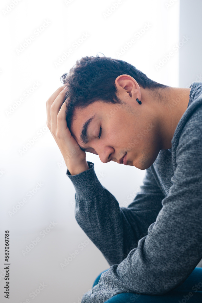 Sad hispanic teenager boy hand on head with closed eyes. Depression ...