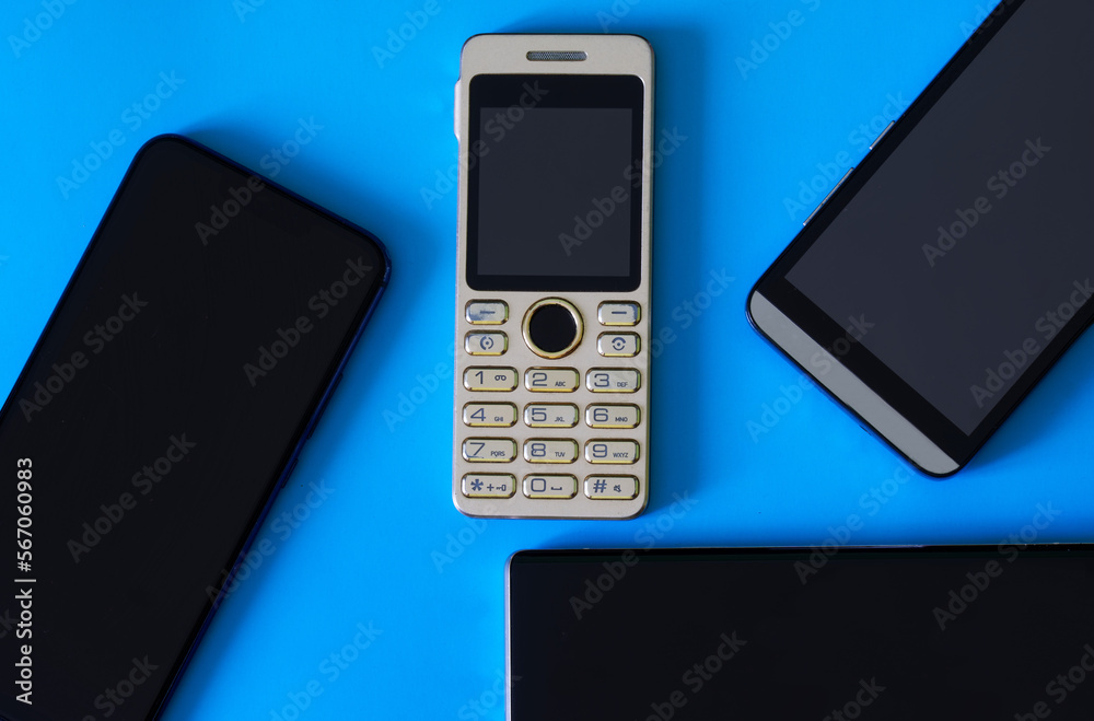 Golden push-button mobile phone compared to smartphones of different ...
