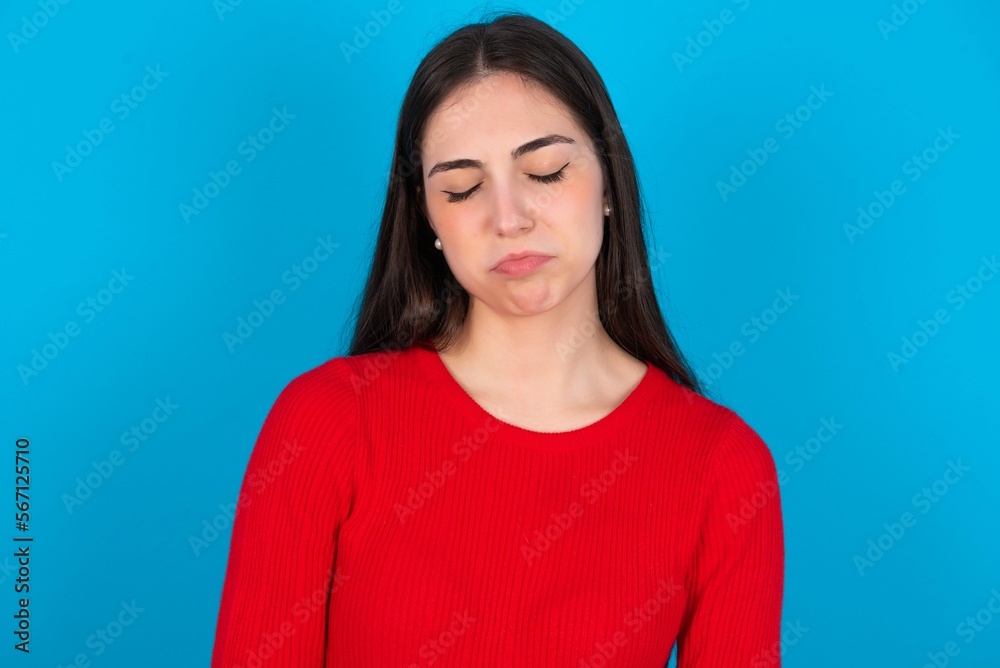 Dismal gloomy rejected young brunette girl wearing red T-shirt against ...