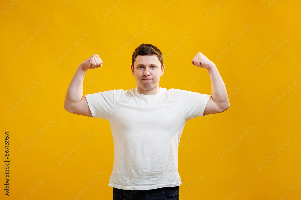 Positive emotional man smiles, shows muscles on his arms, feels proud ...