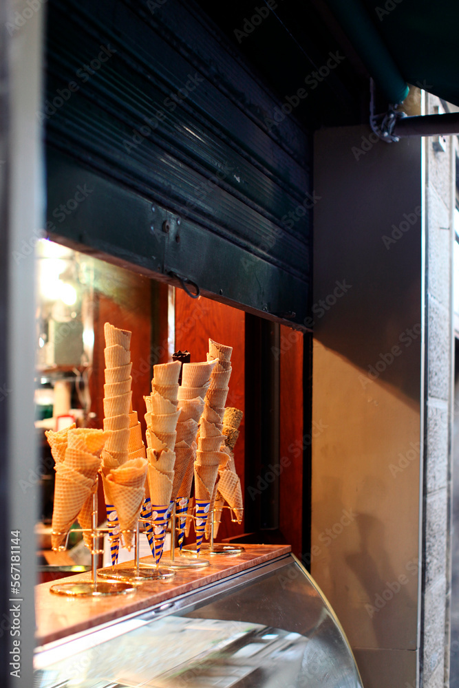 ice cream cones of all shapes and sizes sit in a window of a gelateria ...
