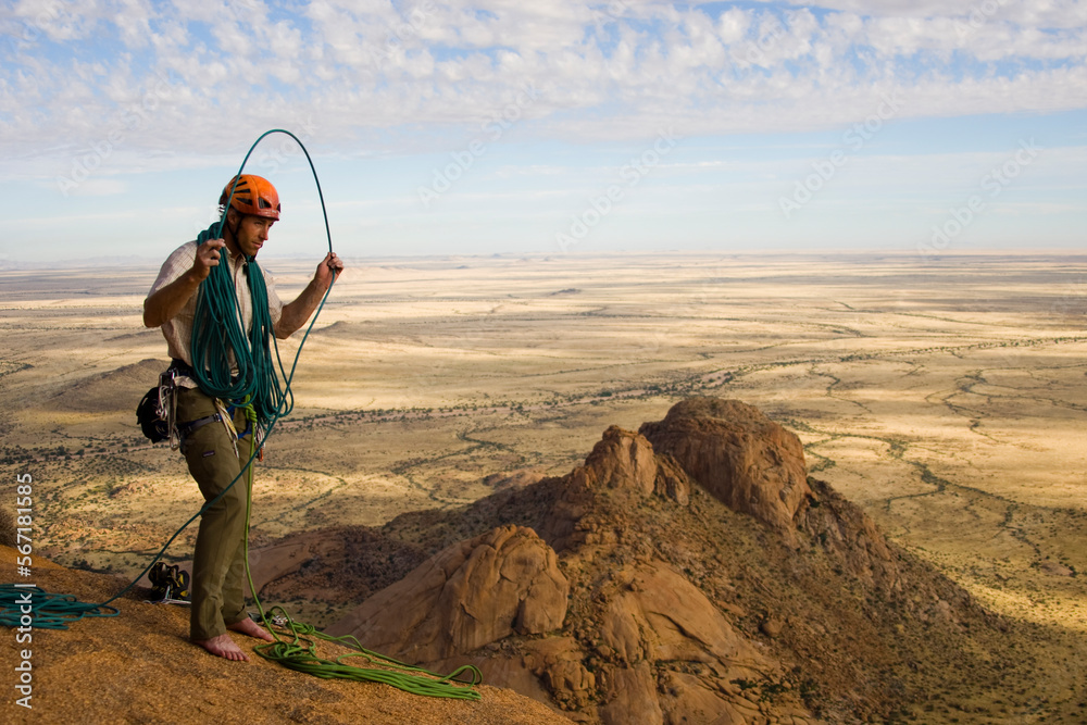 Male climber finishes route and prepares the rope. Bare feet and ...