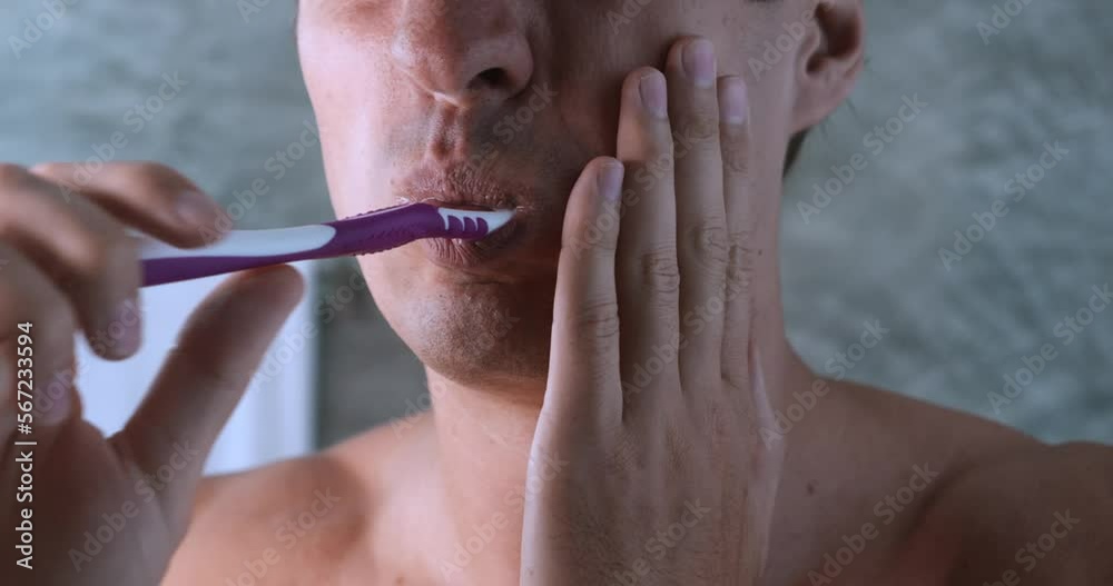 Stockvideon Close up young man suffers from tooth pain when brushes ...