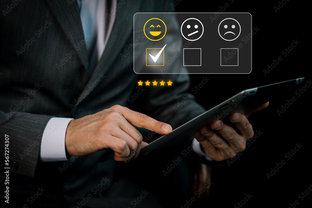 Businessman hand using tablet with popup five star icon and happy smile ...