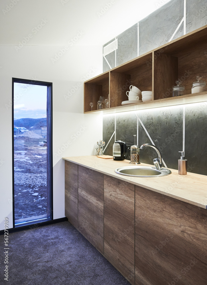 Modern kitchen with white walls and glass door with scenic view inside ...