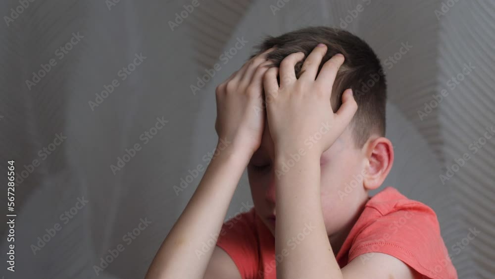 Vidéo Stock a boy of 8-10 years old, covering his face from grief, is ...
