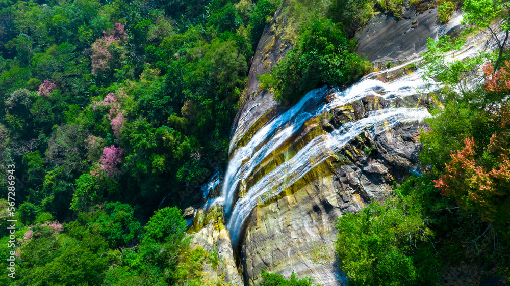 Wide aerial view of waterfall flowing in the depths of the forest ...