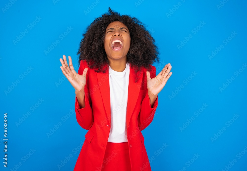 Crazy outraged young businesswoman with afro hairstyle wearing red over ...