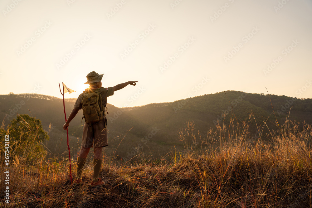 Asian Boy Scout standing on cliff with meadow Scout students point ...