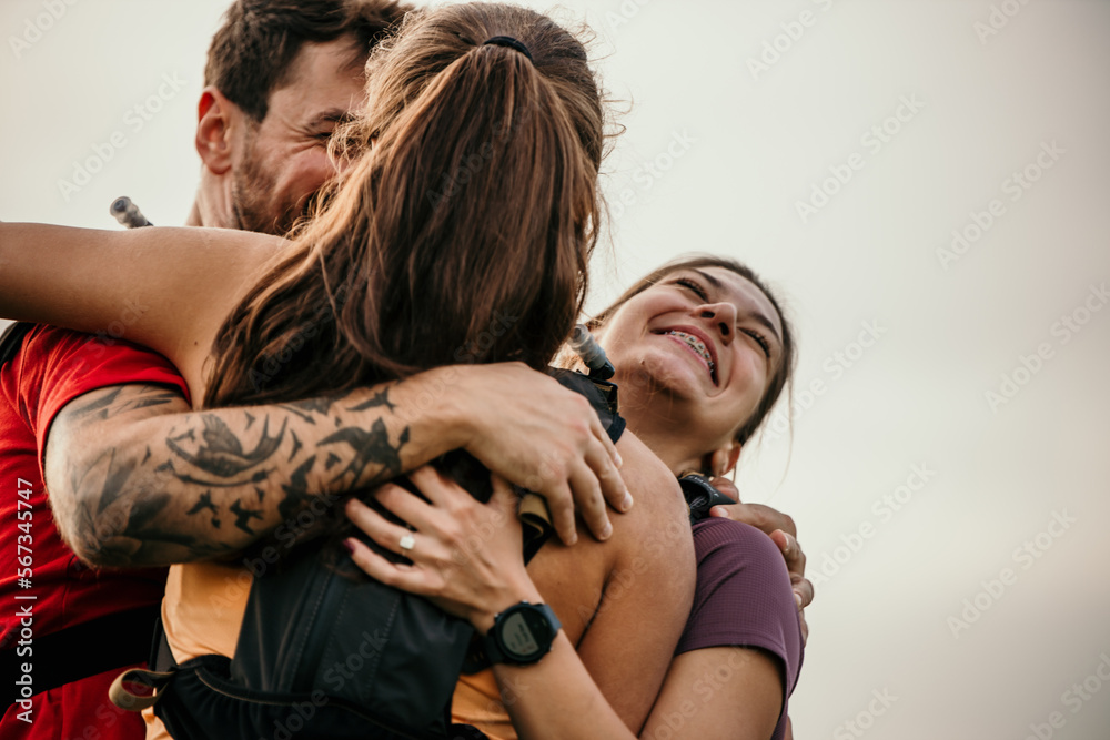 Side view of a group of runners wearing race gear and hugging after a ...