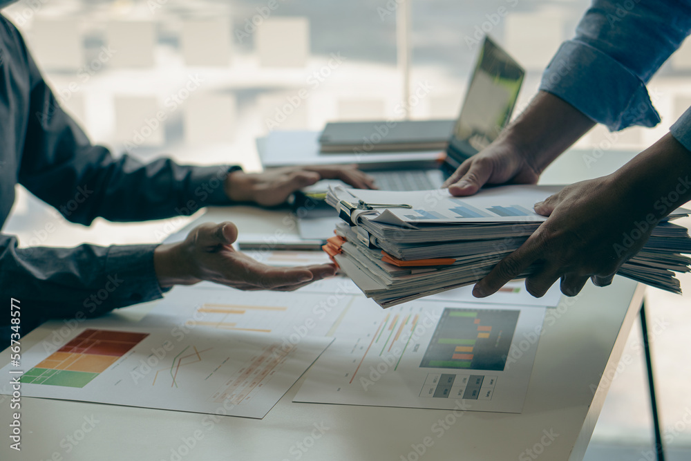 Businessman working in bureaucracy with laptop and documents stacked as ...