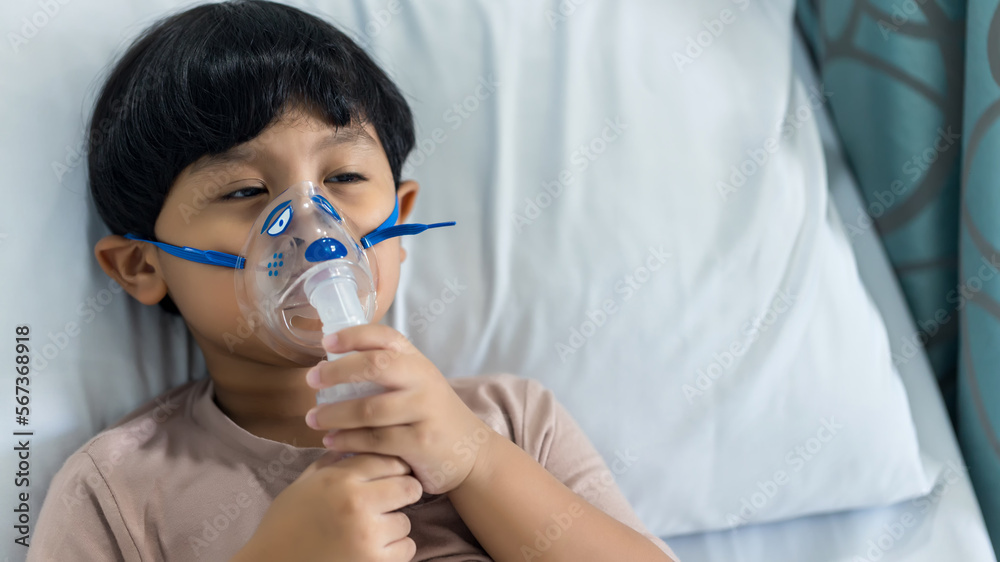 Sick boy inhalation therapy by the mask of inhaler. Baby has asthma and ...