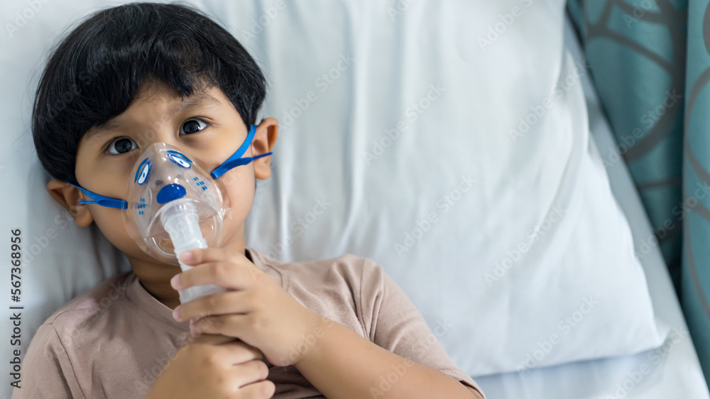 Sick boy inhalation therapy by the mask of inhaler. Baby has asthma and ...