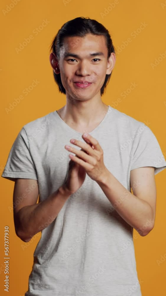 Vertical video: Smiling person clapping hands in studio, laughing and ...