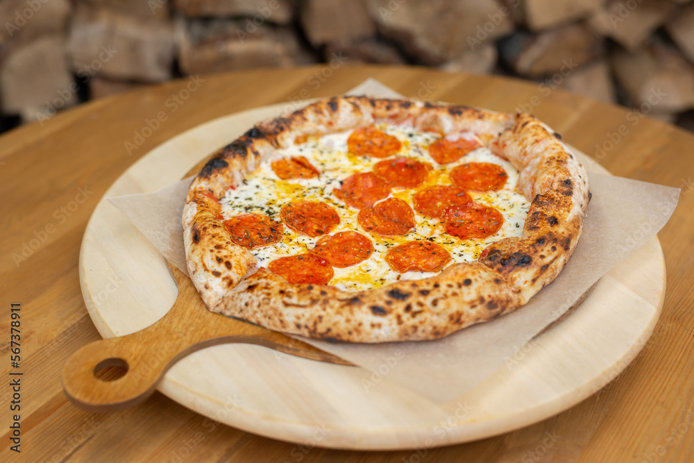 Ready-made Italian pizza on a wooden plate is ready to be served in the ...