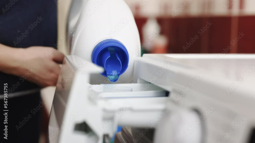 Woman pours necessary amount of white liquid laundry detergent into ...