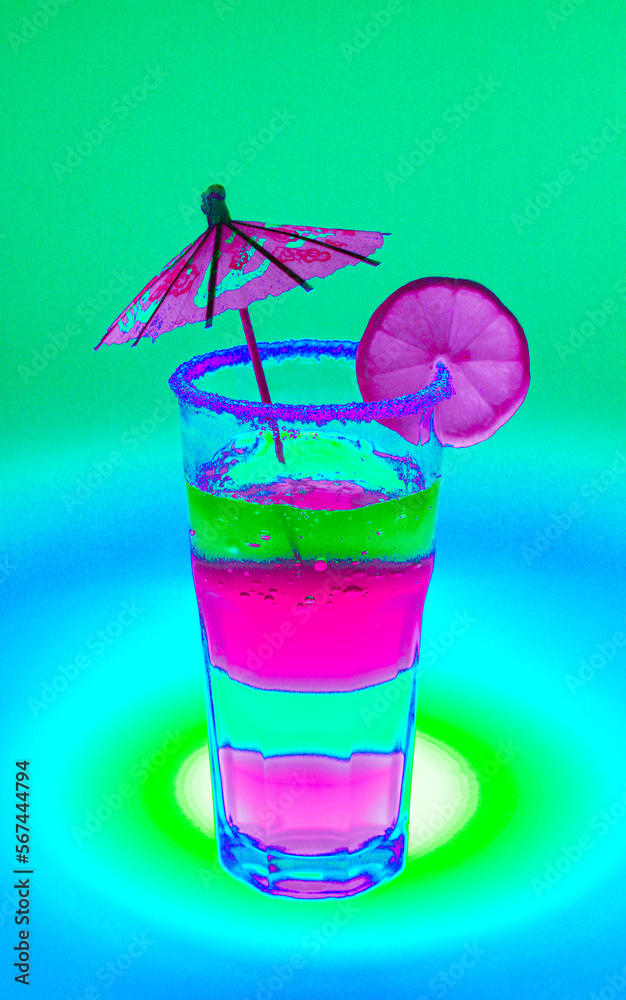 bright rich neon cocktail in a tall glass with an umbrella and a piece ...