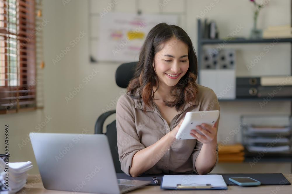 Asian businesswoman working with laptop computer using calculator to ...