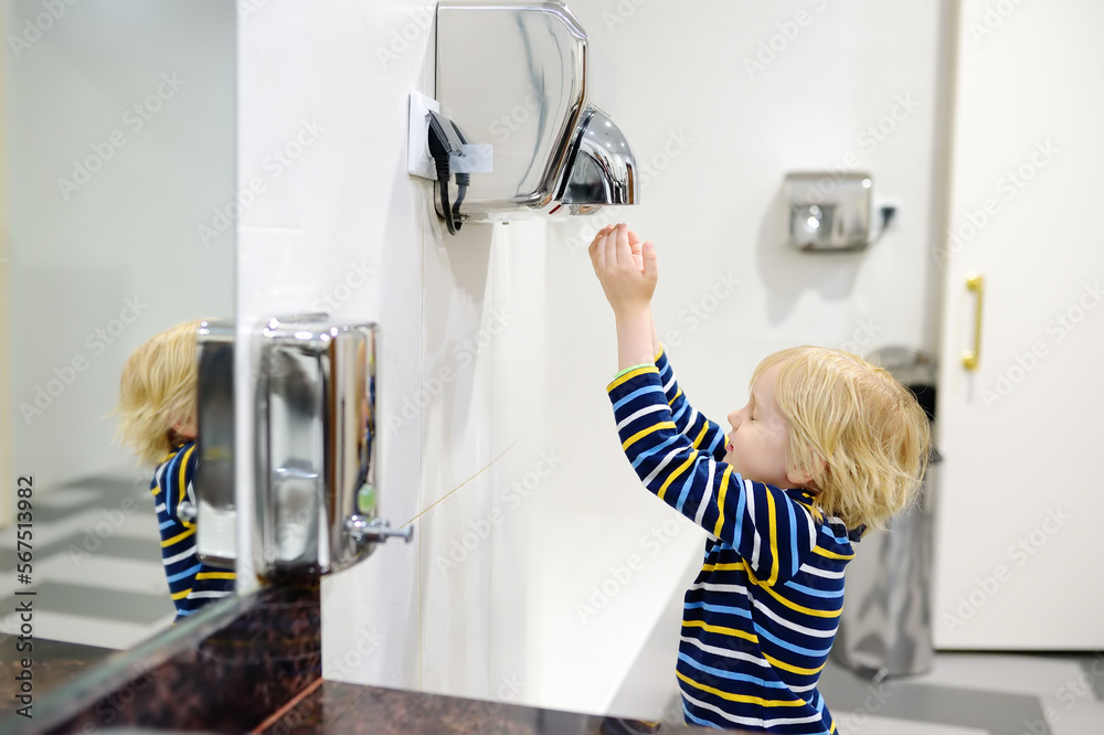 Child using restroom. Little boy dries his hands in the toilet with an ...