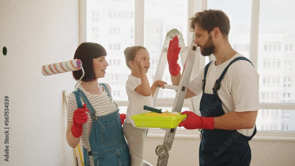 Happy family mother father and child daughter are doing repairs paint ...