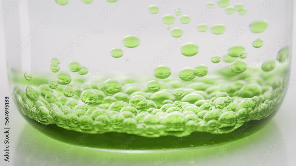 Side view extreme close-up shot of green transparent bubbles sink to ...