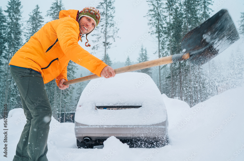 Winter morning routine. Smiling man with a shovel removing snow from ...