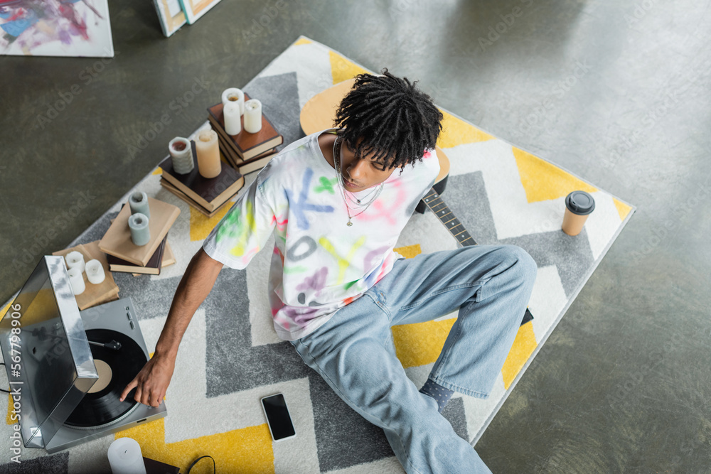 Overhead view of african american artist using record player near books ...