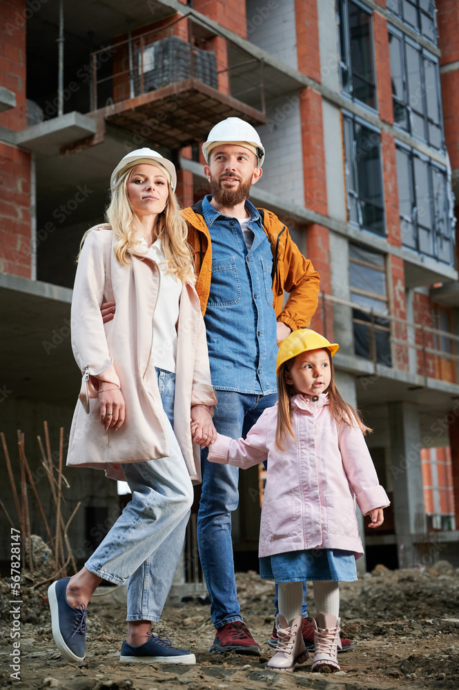 Man, woman and child standing outside building under construction ...
