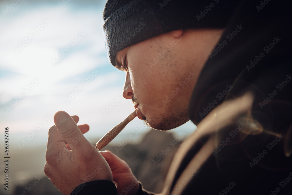 Boy smoking a marijuana joint on top of a mountain during sunset Stock ...