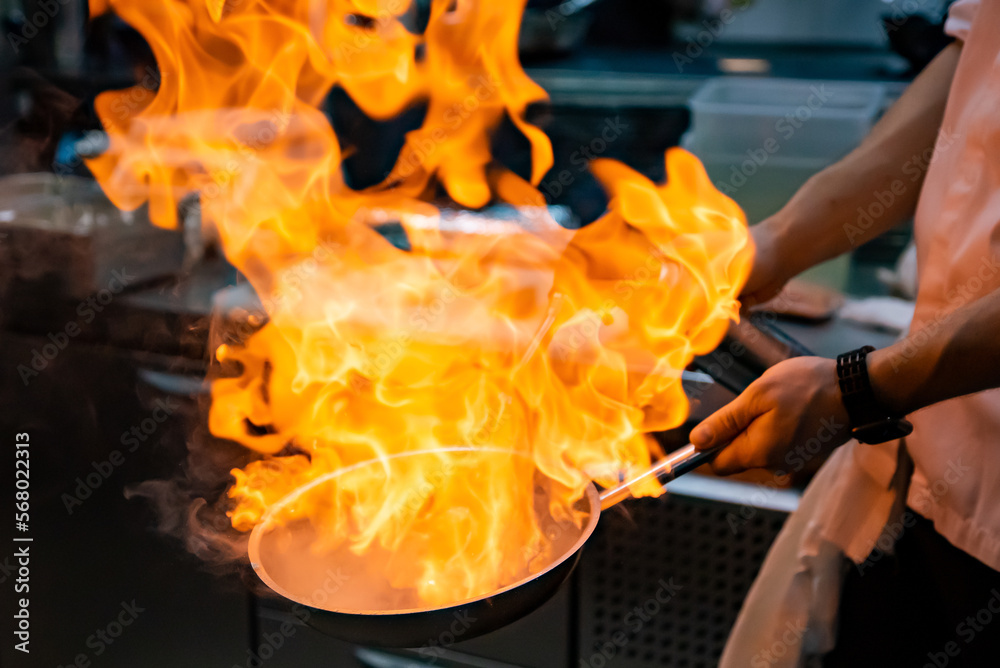 Chef hand in restaurant kitchen with pan, cooking flambe on food Stock ...