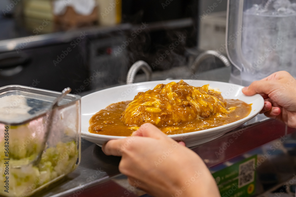 Chef cooking Japanese curry rice with omelette serving to customer on ...