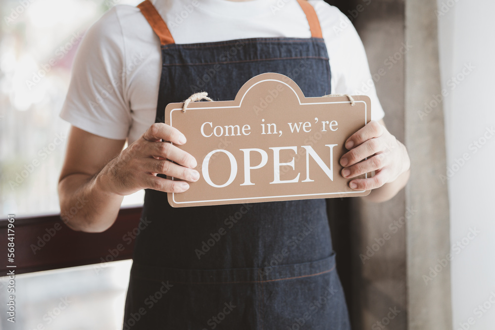 Man holding open/close sign in front of entrance, Goods and Service ...