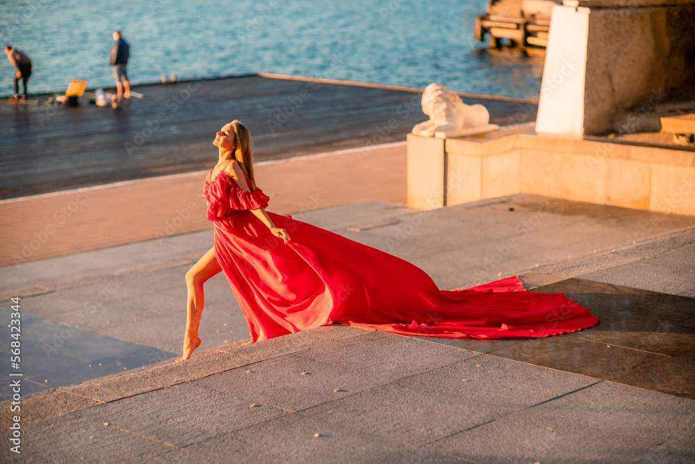 Sunrise red dress. A woman in a long red dress against the backdrop of ...